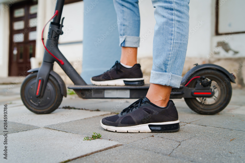Close up on woman legs feet standing on the electric kick scooter on ...