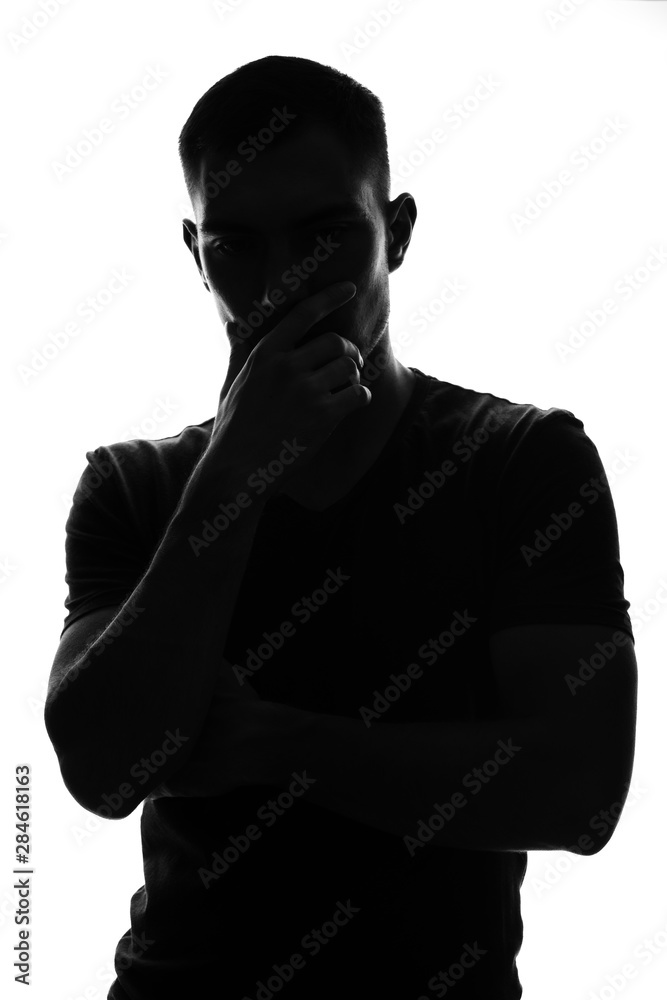 Silhouette portrait of a thoughtful young man holding his hand to his ...
