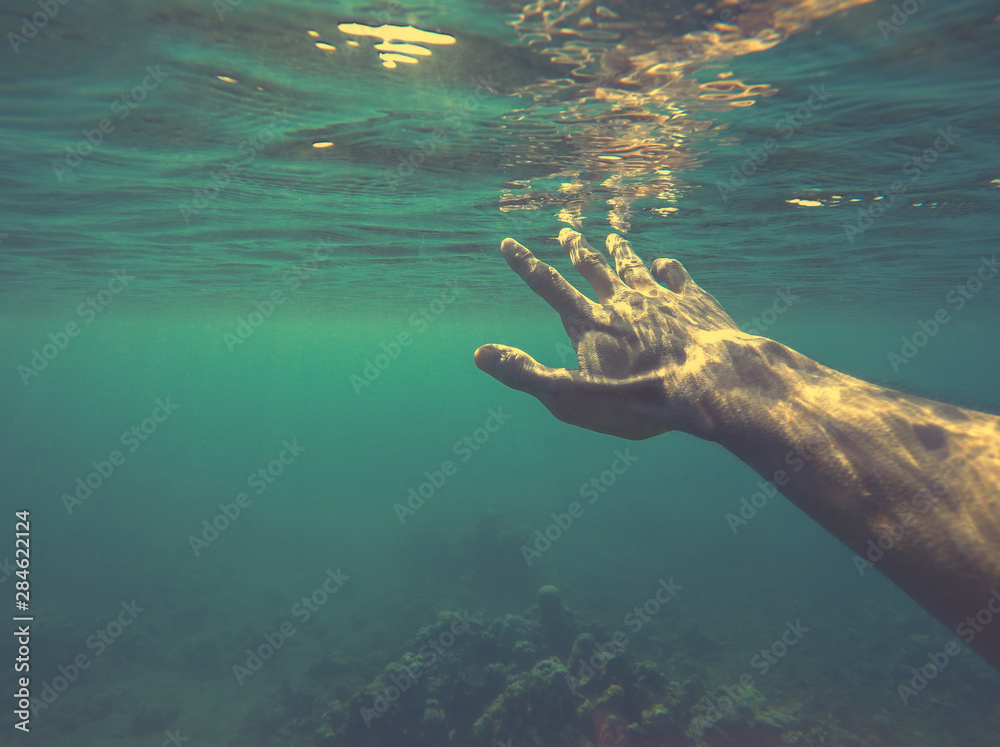 Underwater hand reaching for sun. Man drowning in the sea. Rescue from ...