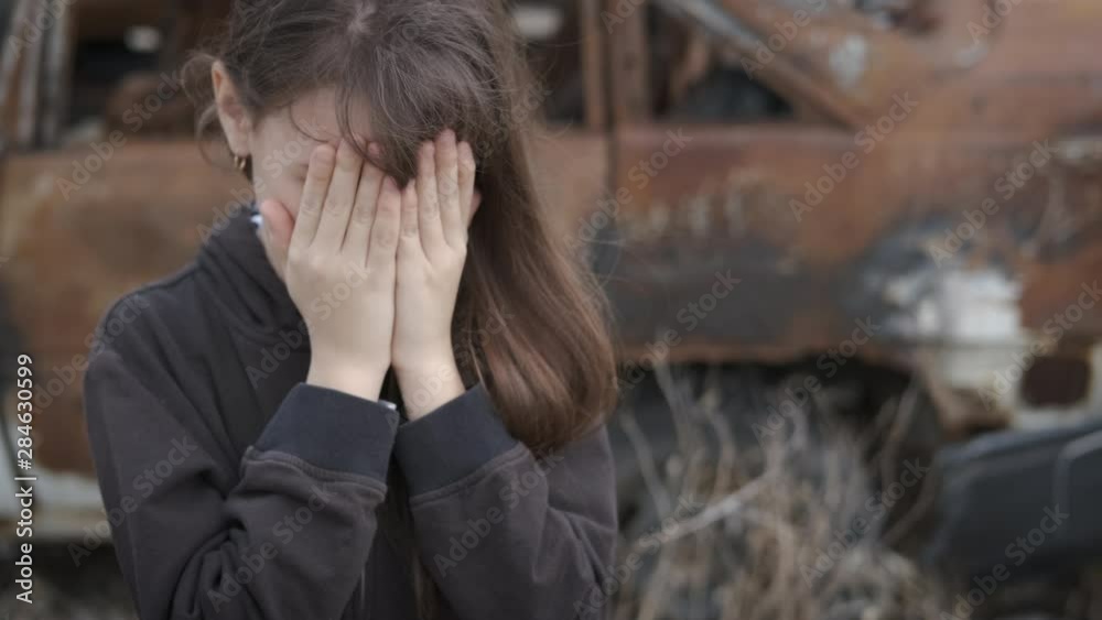 The homeless child is crying. A little orphan girl covered her face in ...