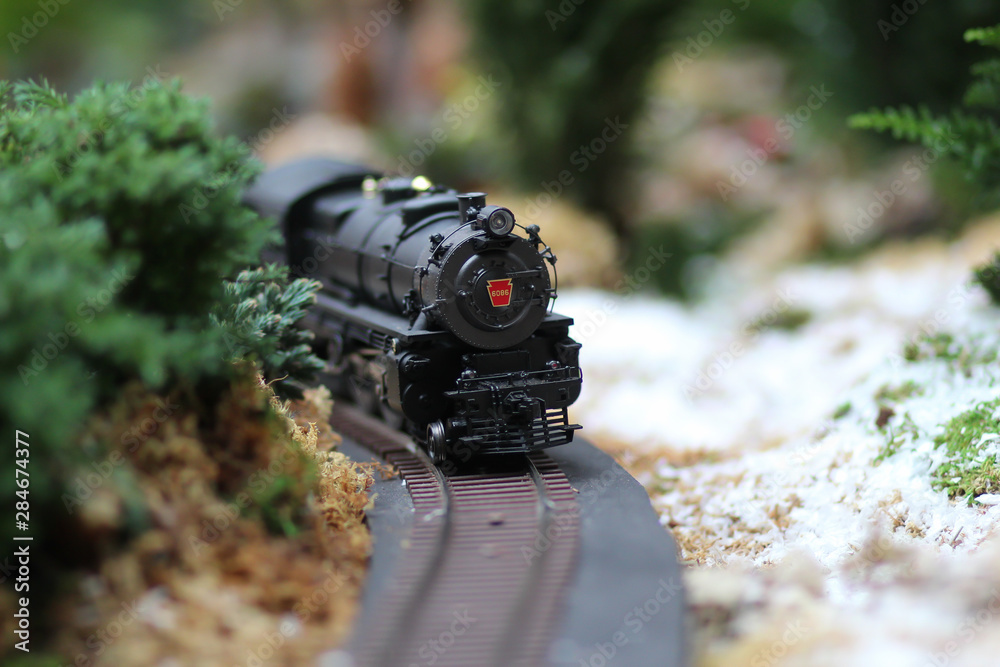 black toy train coming around the corner on a decorated table with ...