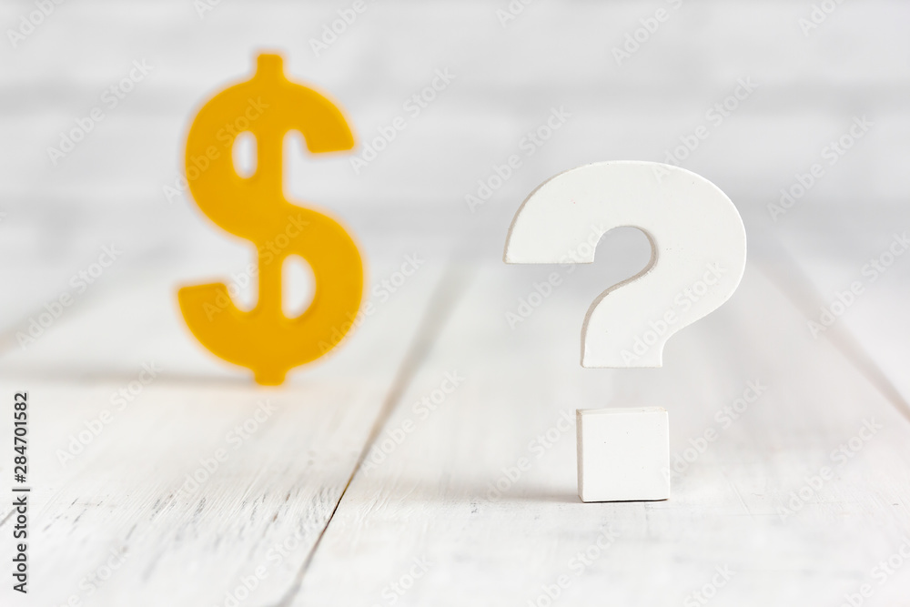 Question mark with dollar sign on white wood table over white brick ...