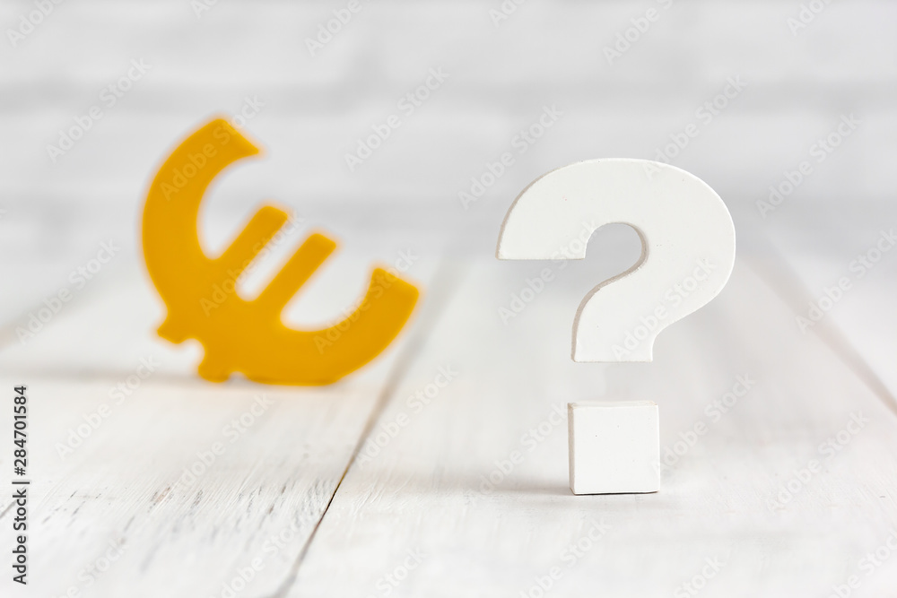 Question mark with euro sign on white wood table over white brick ...