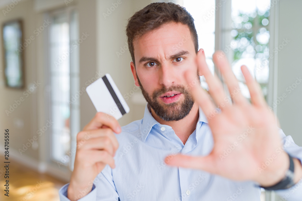 Handsome business man holding credit card with open hand doing stop ...