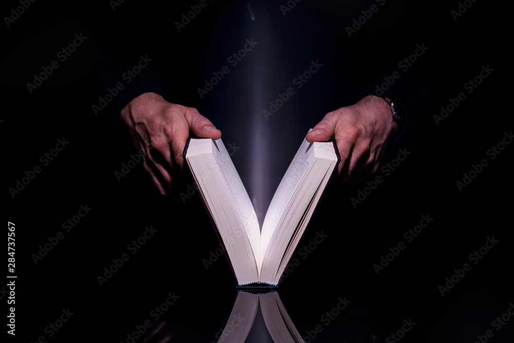 Person reading book with glowing light coming from inside of it. High ...