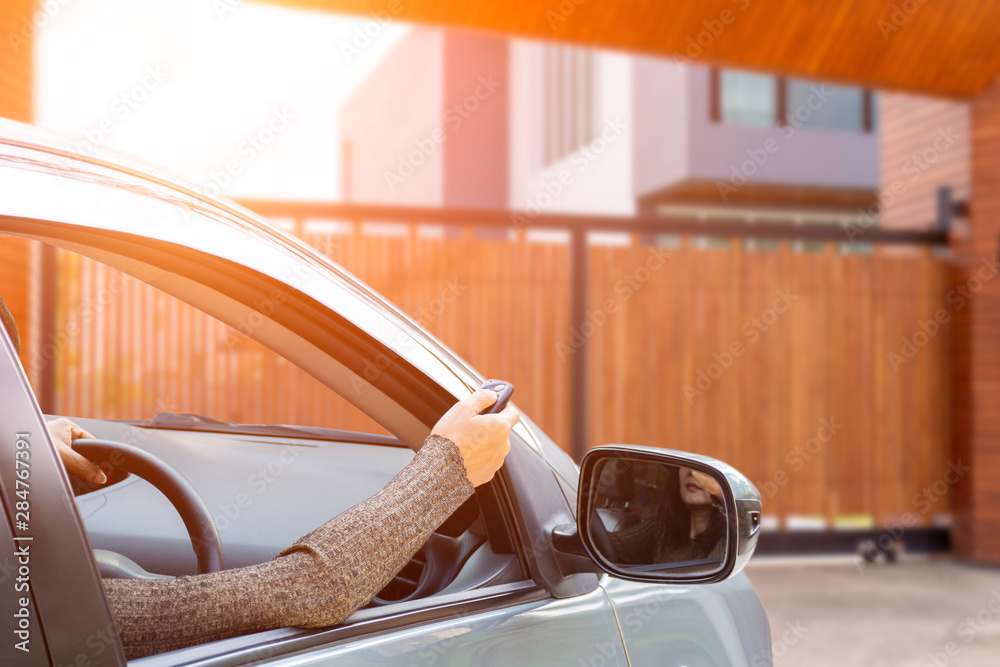 Woman in car, hand using remote control to open auto wooden door with ...