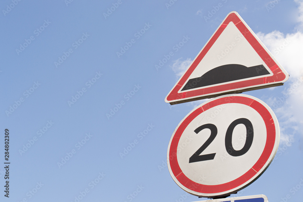 Two road red signs in front of a pedestrian crossing. Speed Limit 20 ...