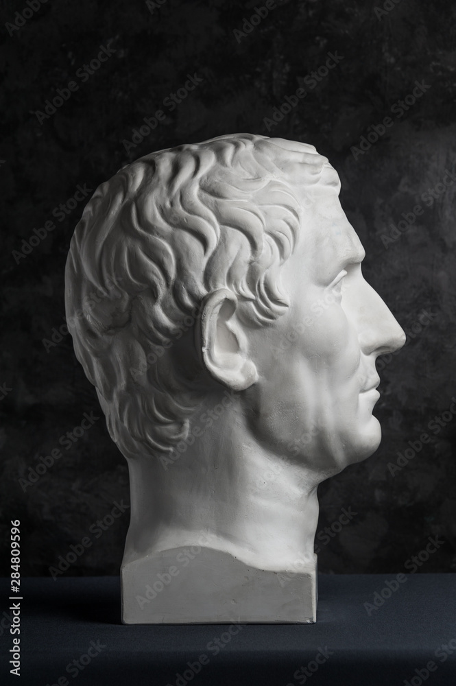 Gypsum copy of ancient statue Augustus head on dark textured background ...