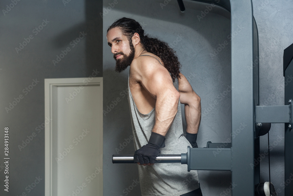 Portrait of powerful confident young adult strong man with long curly ...
