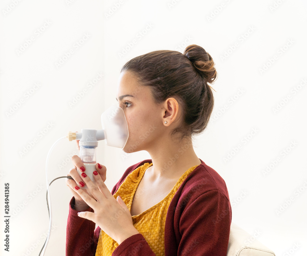 Young woman doing inhalation nebulizer in hospital, holding a mask ...