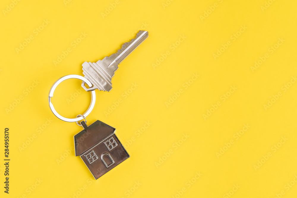 Home key with house keyring or keychain on solid yellow background ...