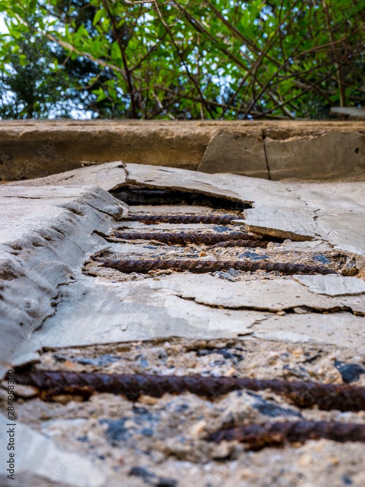 Old crumbling concrete wall with exposed and rusty iron reinforcement ...