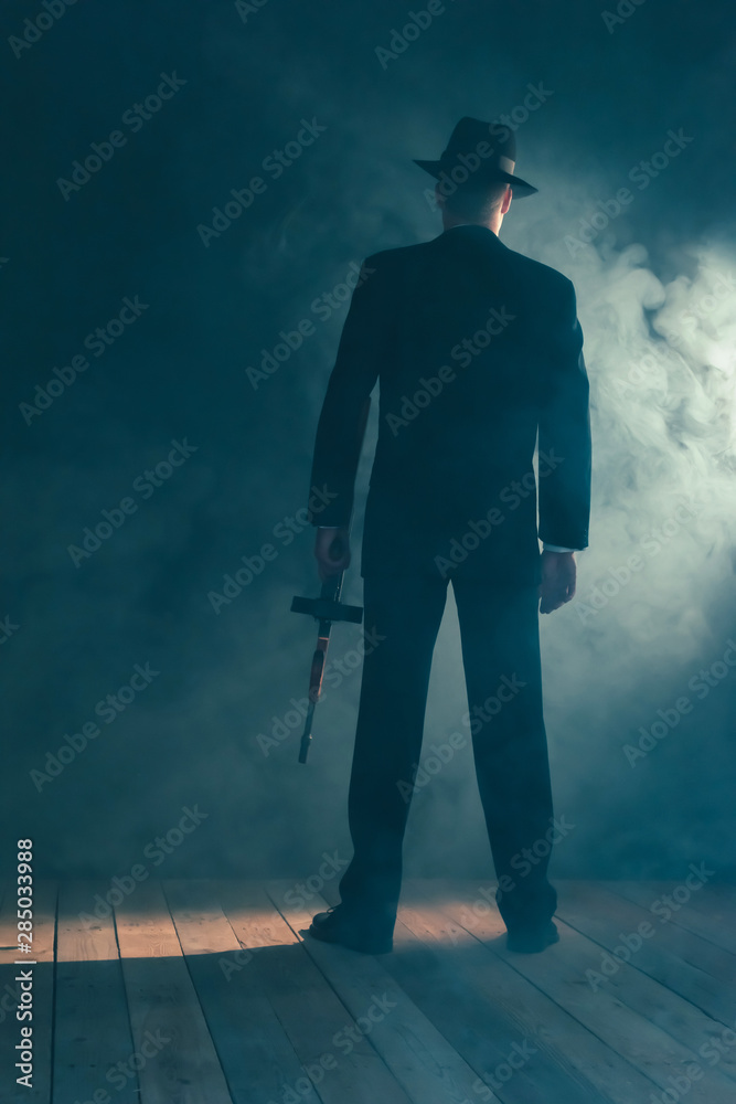 Retro gangster stands with machine gun in smoky room. Rear view. Stock ...