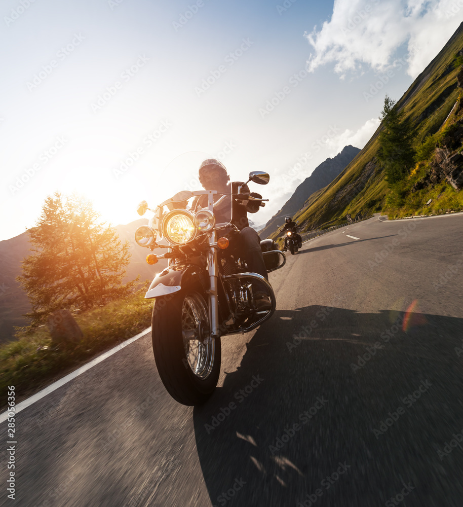 Motorcycle driver riding in Alpine landscape. Stock Photo | Adobe Stock