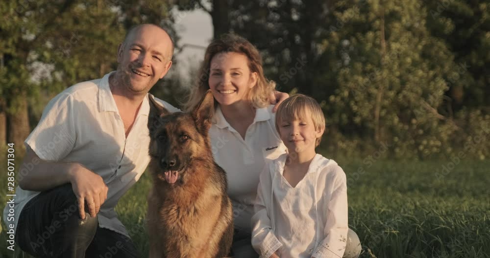 Happy family with a dog in nature. 7 year old boy with his parents ...