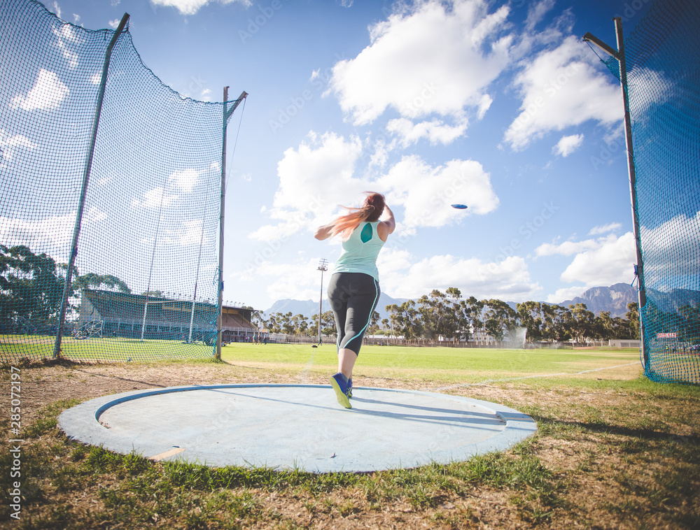 Wide angle action photo of a female discus athlete throwing a discus ...