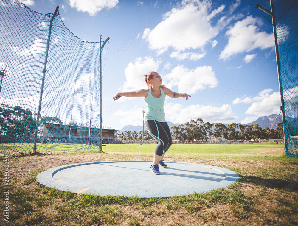 Wide angle action photo of a female discus athlete throwing a discus ...