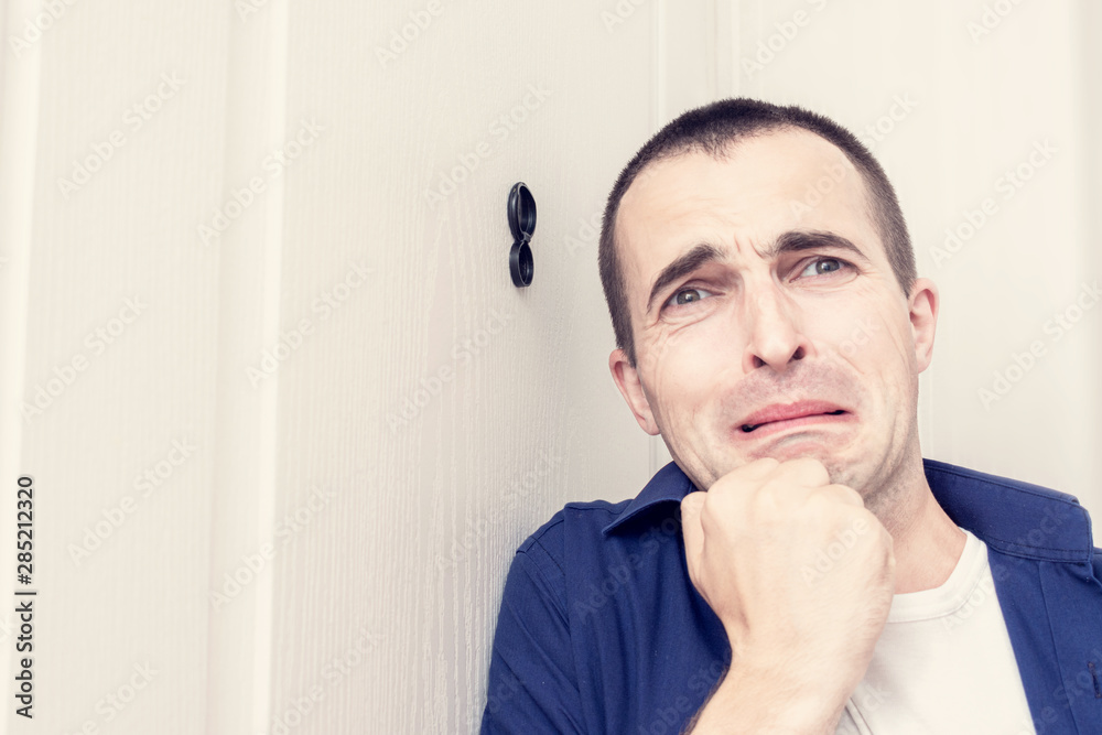 Scared man at the front door, man is terrified and afraid to open the ...