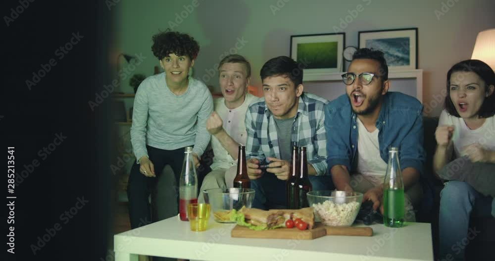 Joyful friends multiracial group are playing video game celebrating ...
