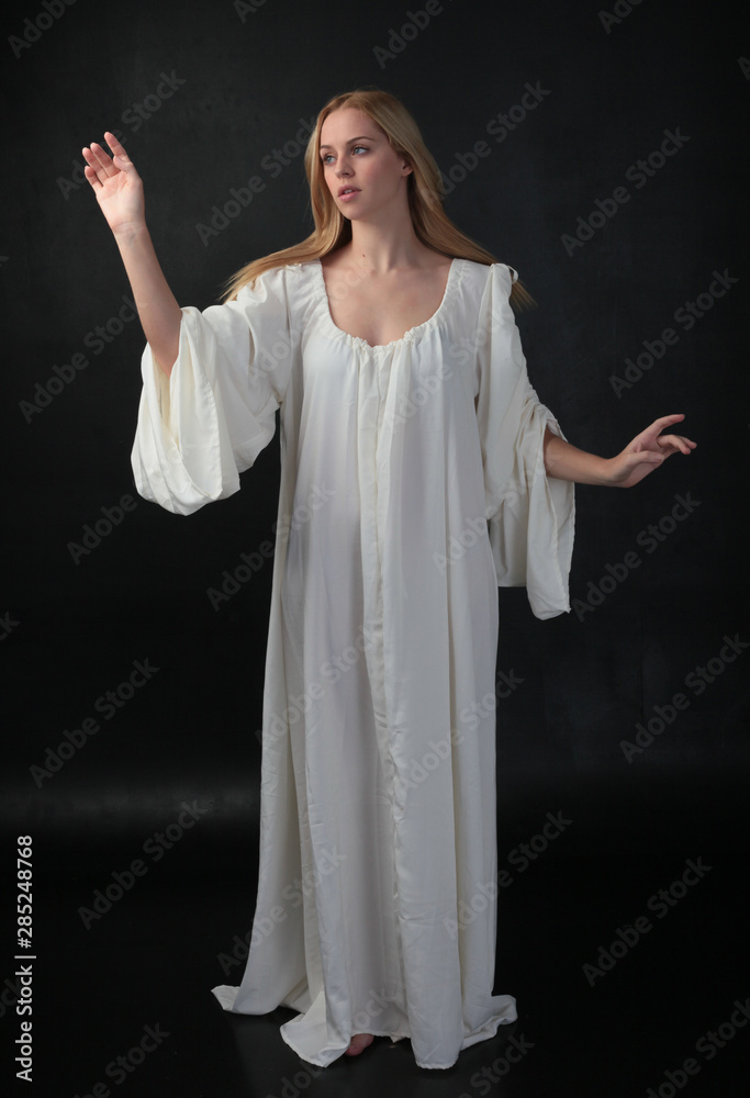 full length portrait of blonde girl wearing long white flowing robe ...