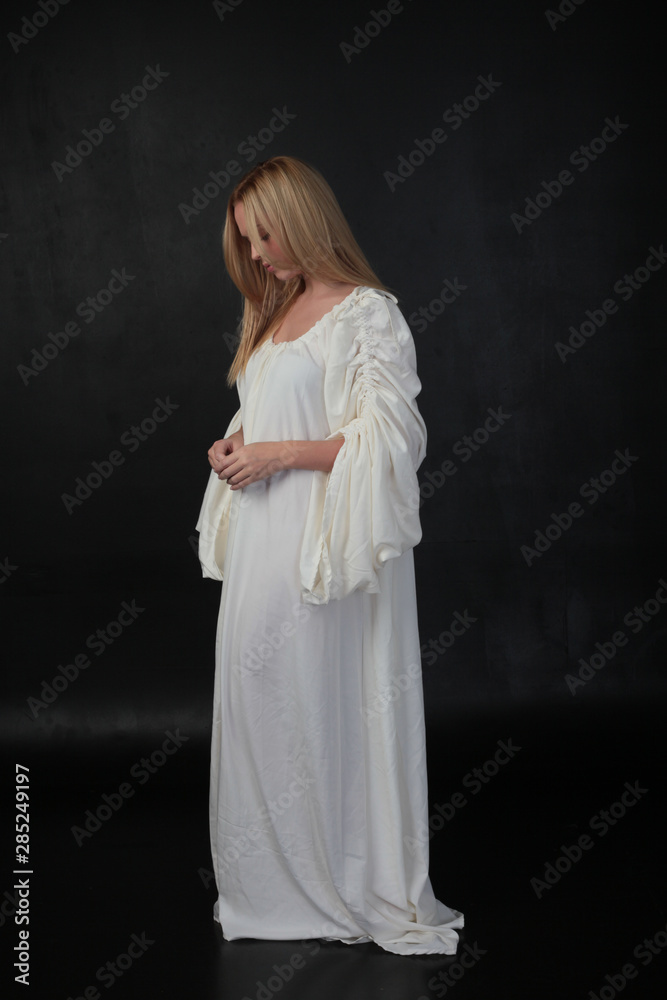 full length portrait of blonde girl wearing long white flowing robe ...