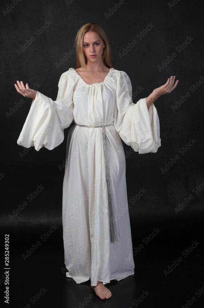 full length portrait of blonde girl wearing long white flowing robe ...