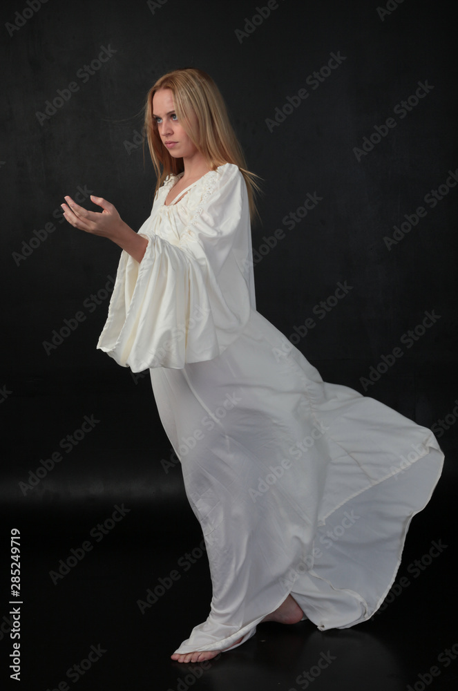 full length portrait of blonde girl wearing long white flowing robe ...