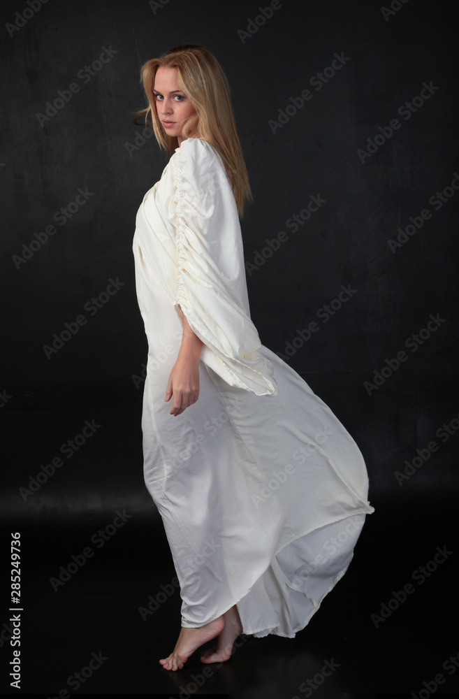 full length portrait of blonde girl wearing long white flowing robe ...