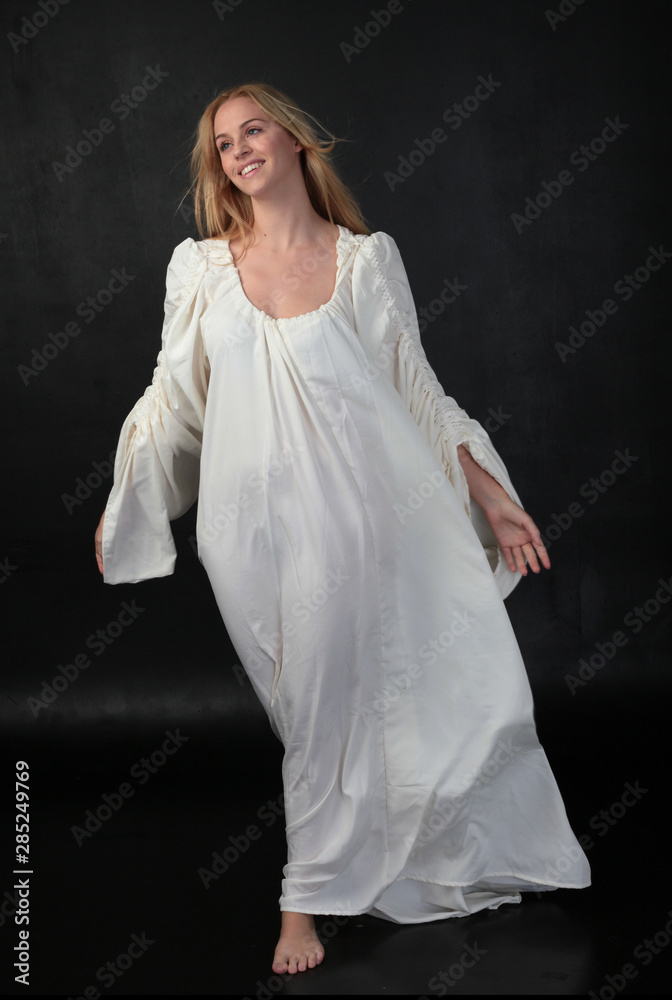 full length portrait of blonde girl wearing long white flowing robe ...