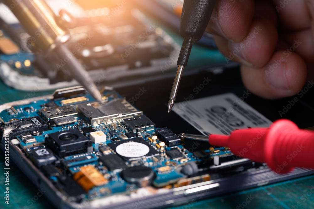 The asian technician repairing the smartphone's motherboard in the lab ...
