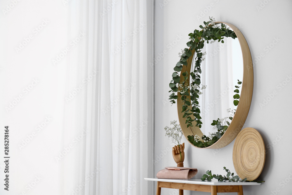 Round mirror and table with accessories near white wall. Modern ...