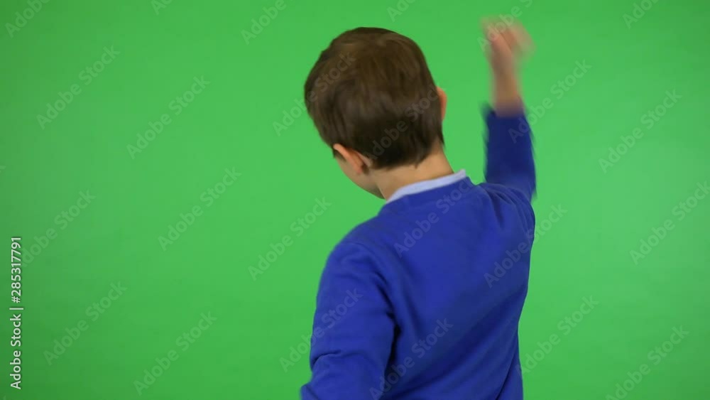 Vidéo Stock A young cute boy is turned with back to the camera, looks ...