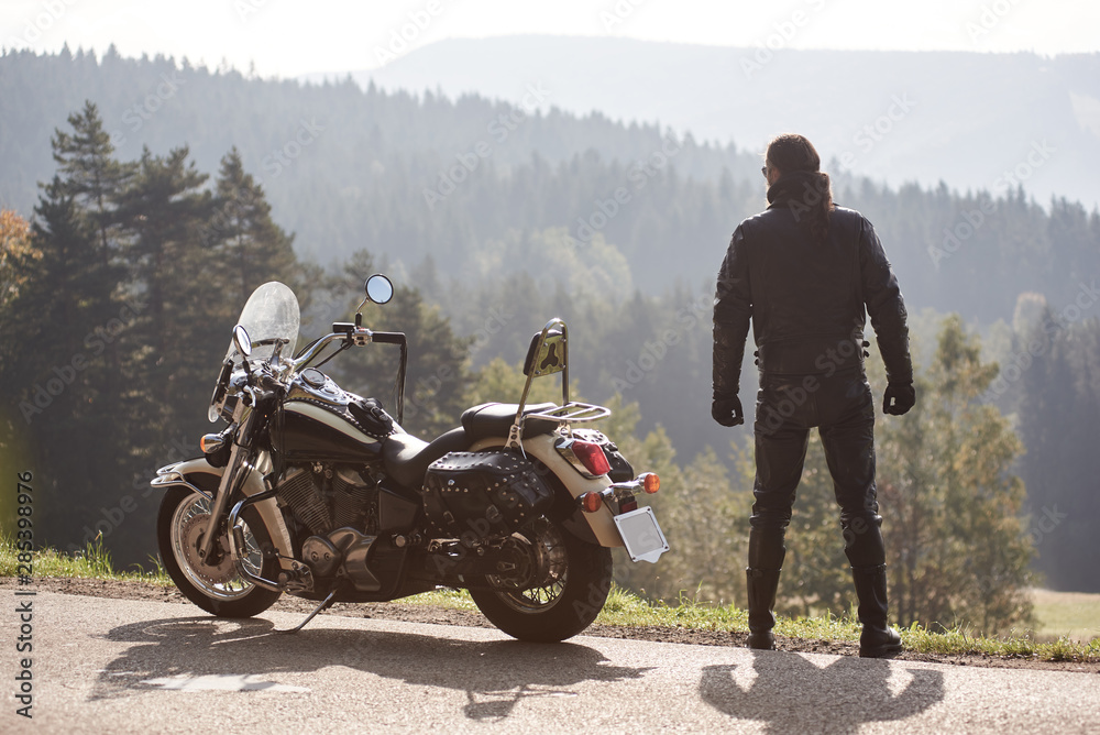 Back view of tall athletic sportive muscular motorcyclist in black ...