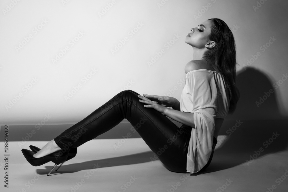 Sexy Girl In Leggings And Top Sits On The Floor And Strokes Her Body