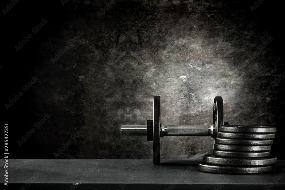 Dumbbell, barbell and workout in the gym. Copy space on black grunge ...