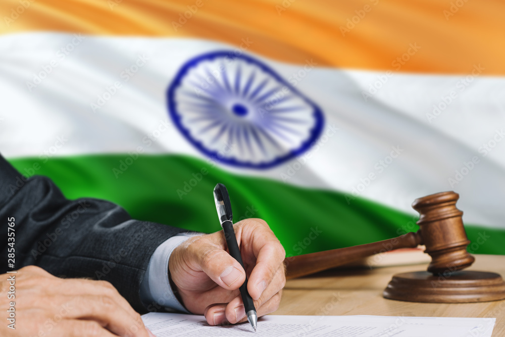 Judge writing on paper in courtroom with India flag background. Wooden ...