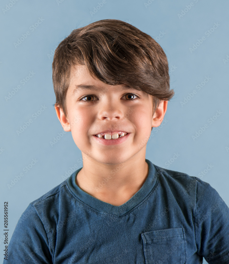 Smiling young boy with big grown up teeth isolated on blue background ...