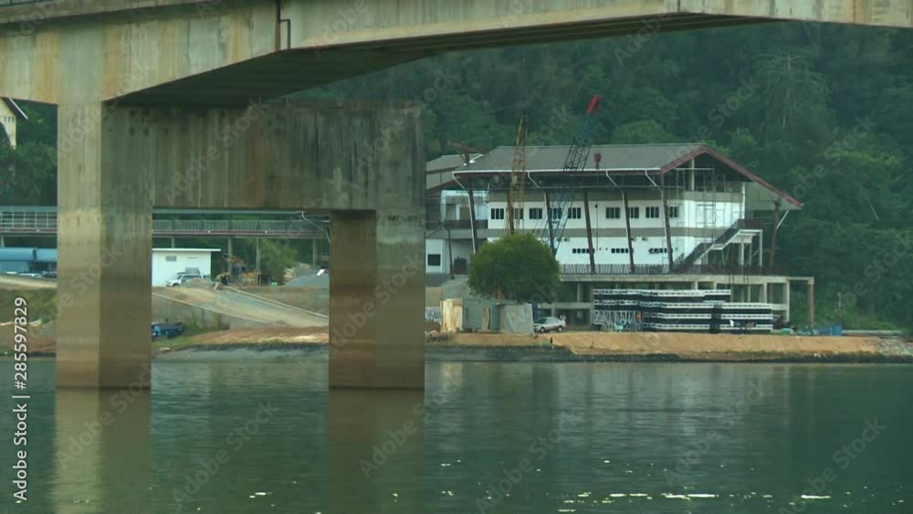 Wide low-angle still shot from below a concrete Highway bridge on Lake ...