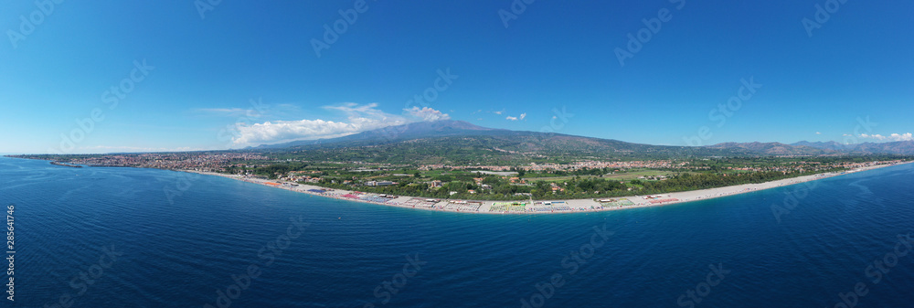 Veduta in estate della spiaggia di Fondachello con sfondo sul vulcano ...