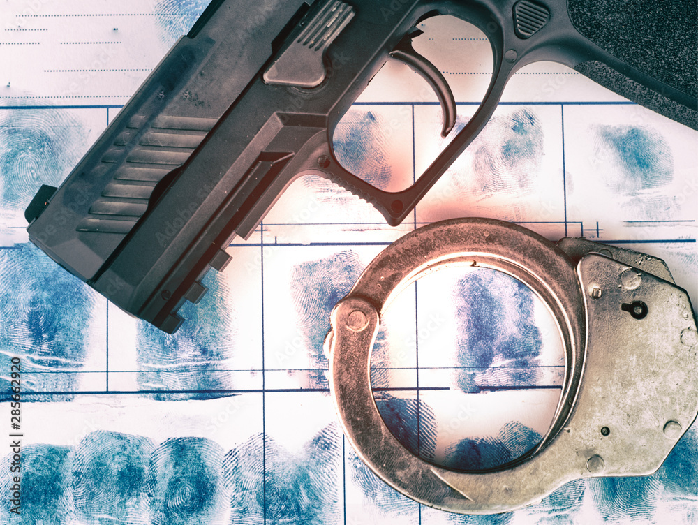 Crime and violence concept.Gun and Police Handcuffs on fingerprints ...