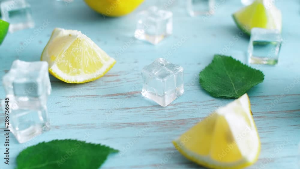 Close up of fresh sliced lime and lemon with ice cubes and green leaves ...
