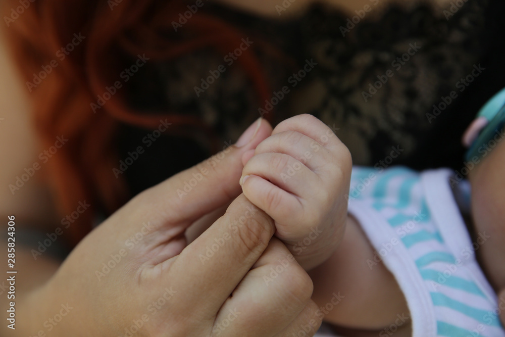 Tiny newborn baby arm in his mother's palm in warm colors in soft focus ...
