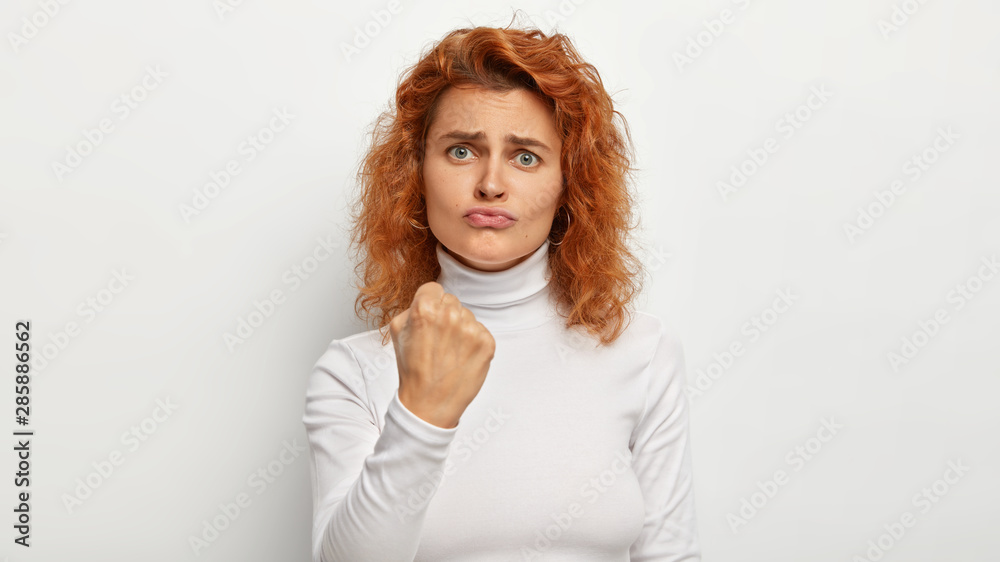 Angry aggressive ginger woman threatens with clenched fist at camera ...