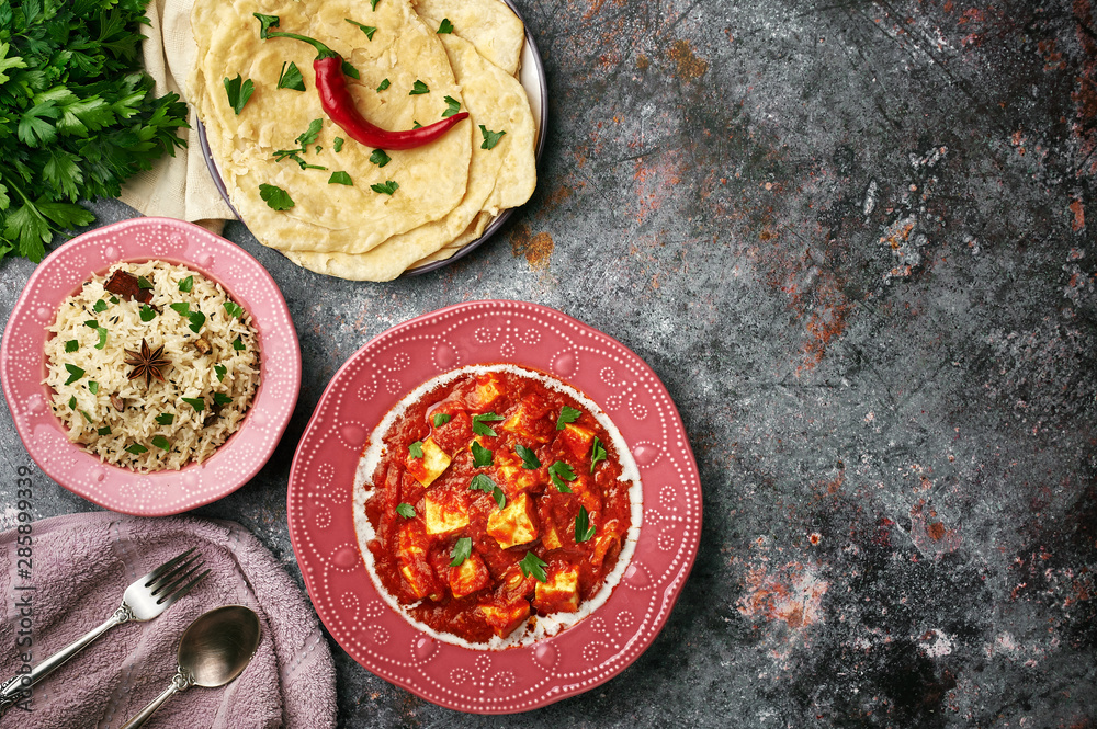 Paneer Makhani, Jeera Rice and paratha in pink plate on dark background ...