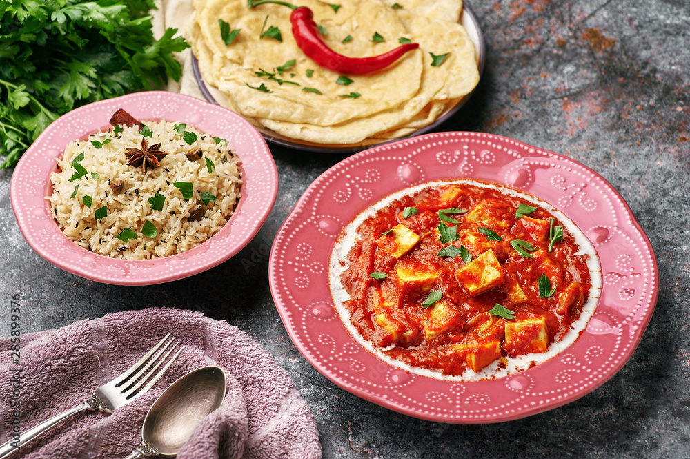 Paneer Makhani, Jeera Rice and paratha in pink plate on dark background ...