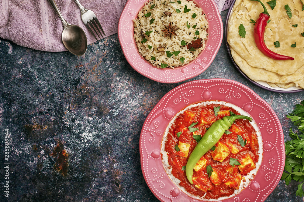 Paneer Makhani, Jeera Rice and paratha in pink plate on dark background ...