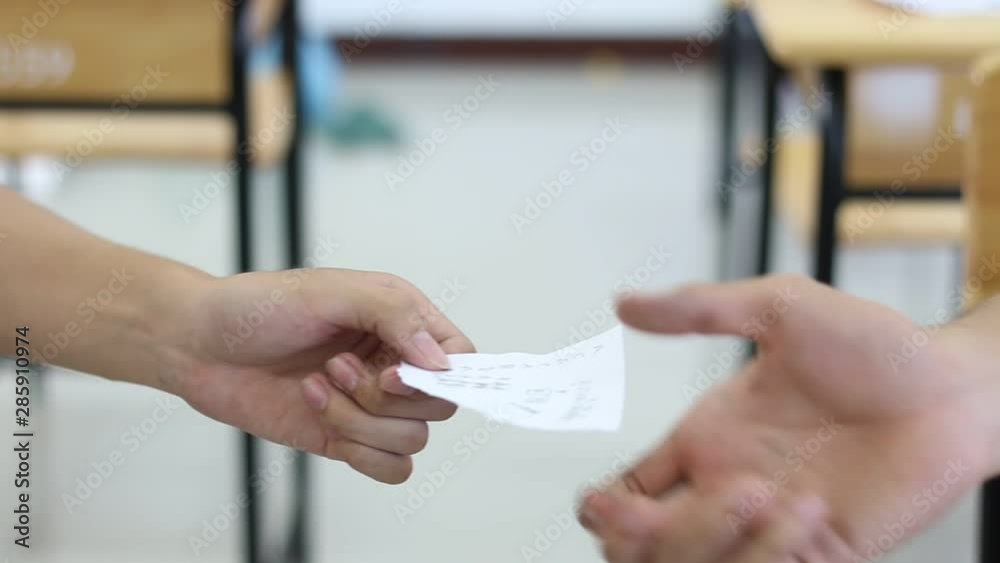 students giving note in cheating exam during examination in classroom ...