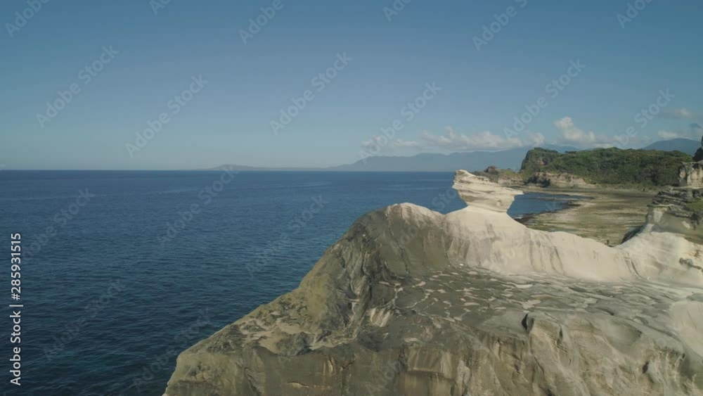 Natural rock formation of limestone stone on the coast with windmills ...