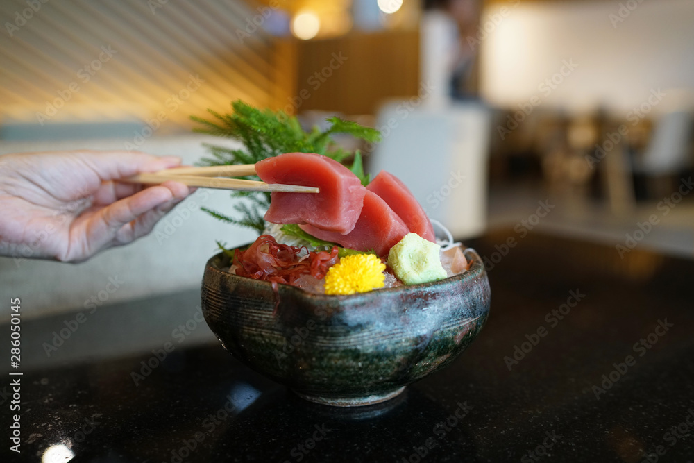 Hand holding chopsticks to pick sashimi - Honmaguro akami sashimi with ...