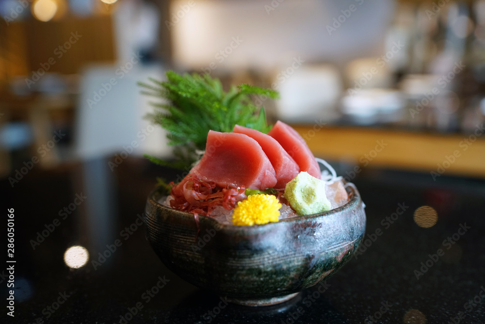 Hand holding chopsticks to pick sashimi - Honmaguro akami sashimi with ...